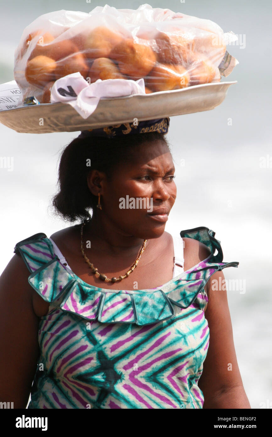 Close up of Ghanaian black native woman carrying dish with merchandise ...