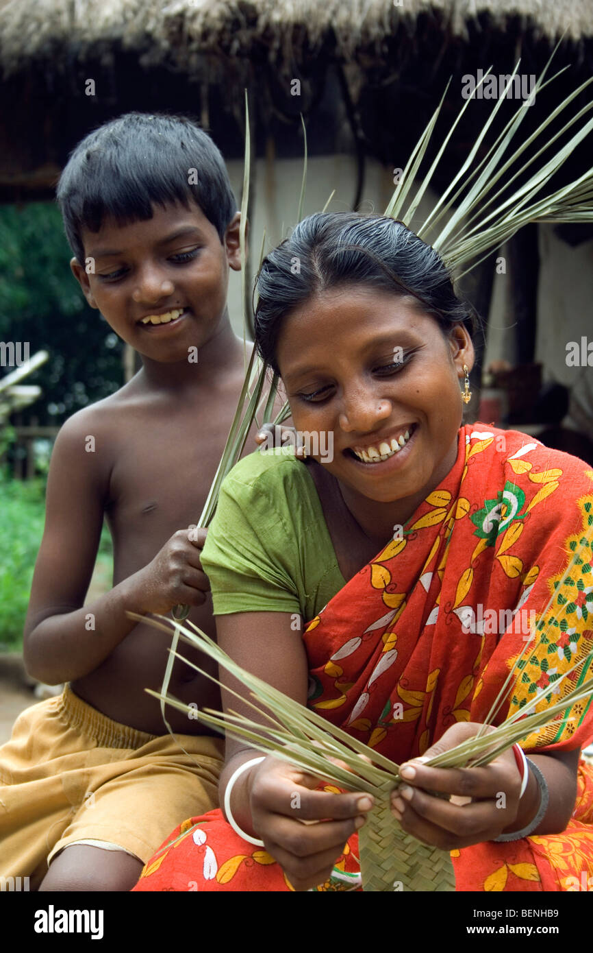 A tribal woman weaving while her son is watching West Bengal India ...