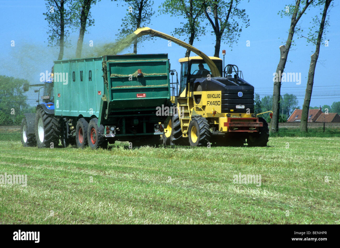 Farming machine and tractor harvest grass in meadow, Belgium Stock ...