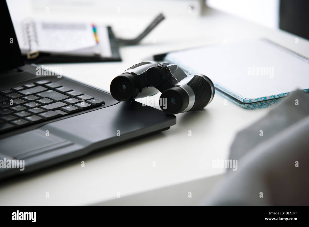 Binoculars on desk with laptop computer and notebook Stock Photo - Alamy