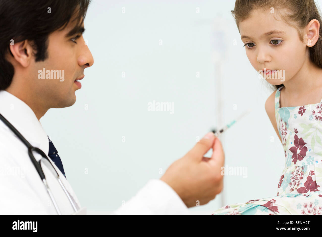 Pediatrician showing little girl syringe Stock Photo - Alamy