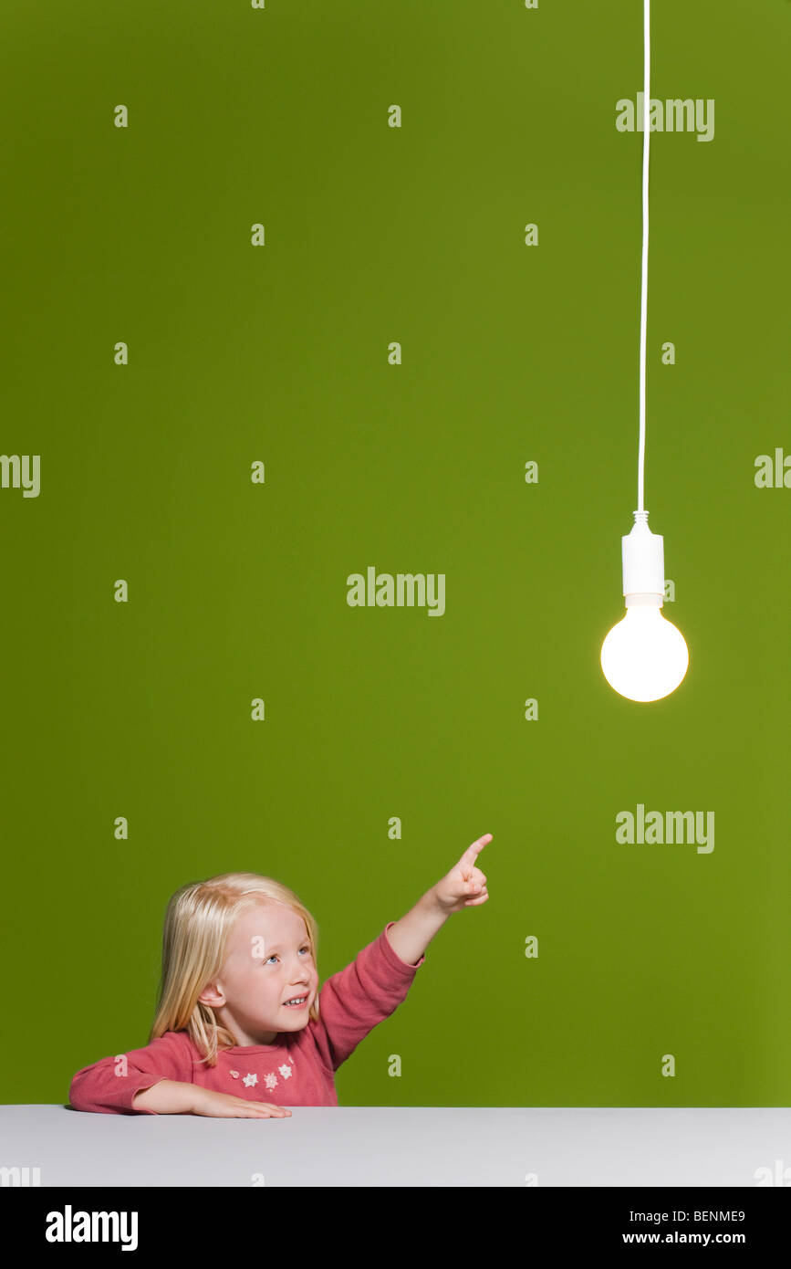Little girl pointing at illuminated light bulb suspended overhead Stock ...