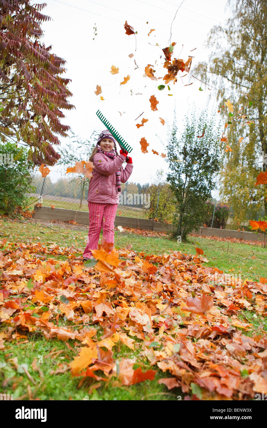 Little girl rake colorful fallen autumn leaves in garden Stock Photo ...
