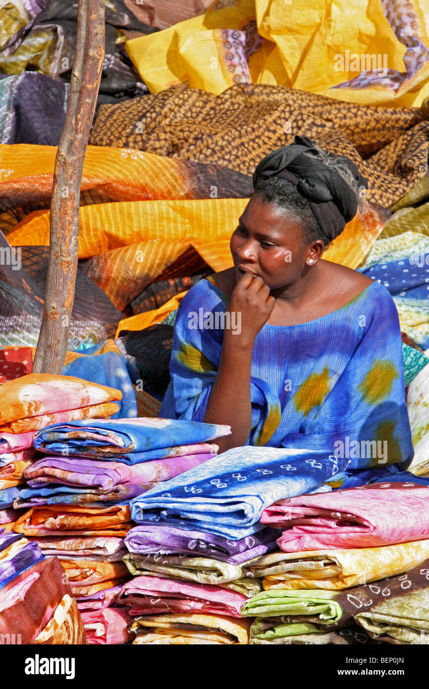 Black woman in traditional clothing selling colourful cloths on market ...