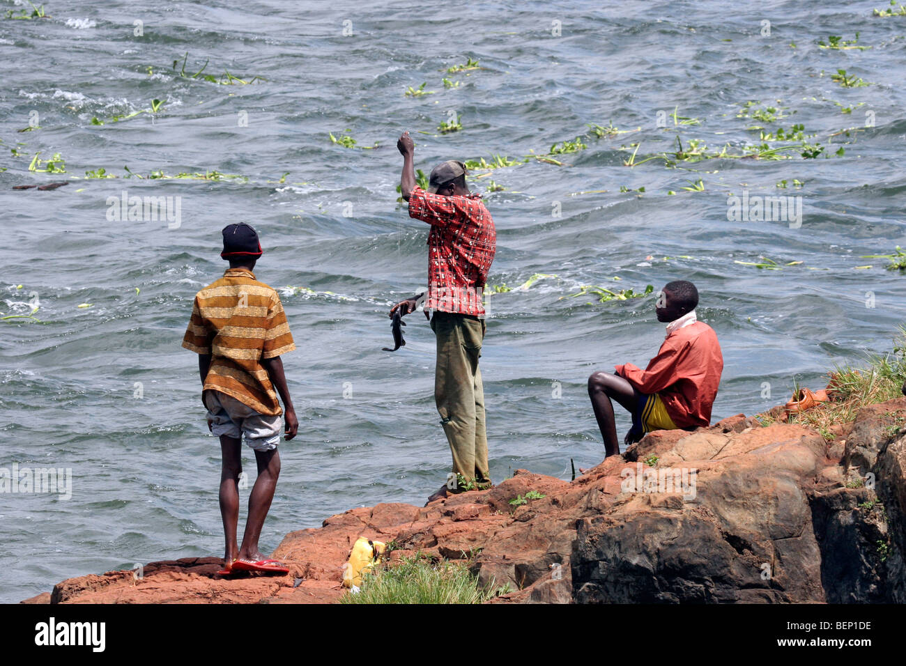 Three black men fishing on the shore of the river White Nile / Victoria ...