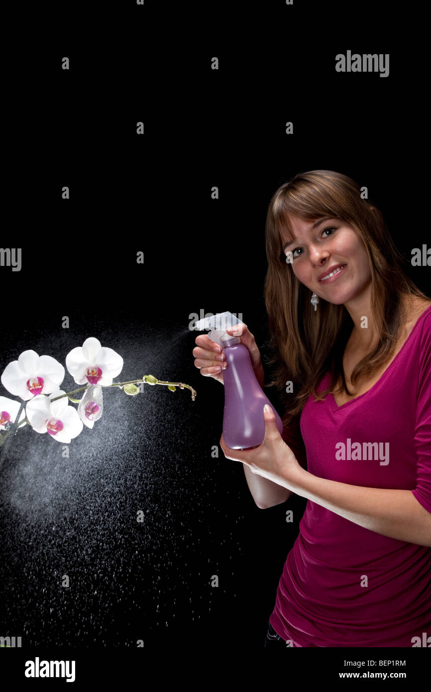 pretty young woman spraying water at an orchid Stock Photo - Alamy