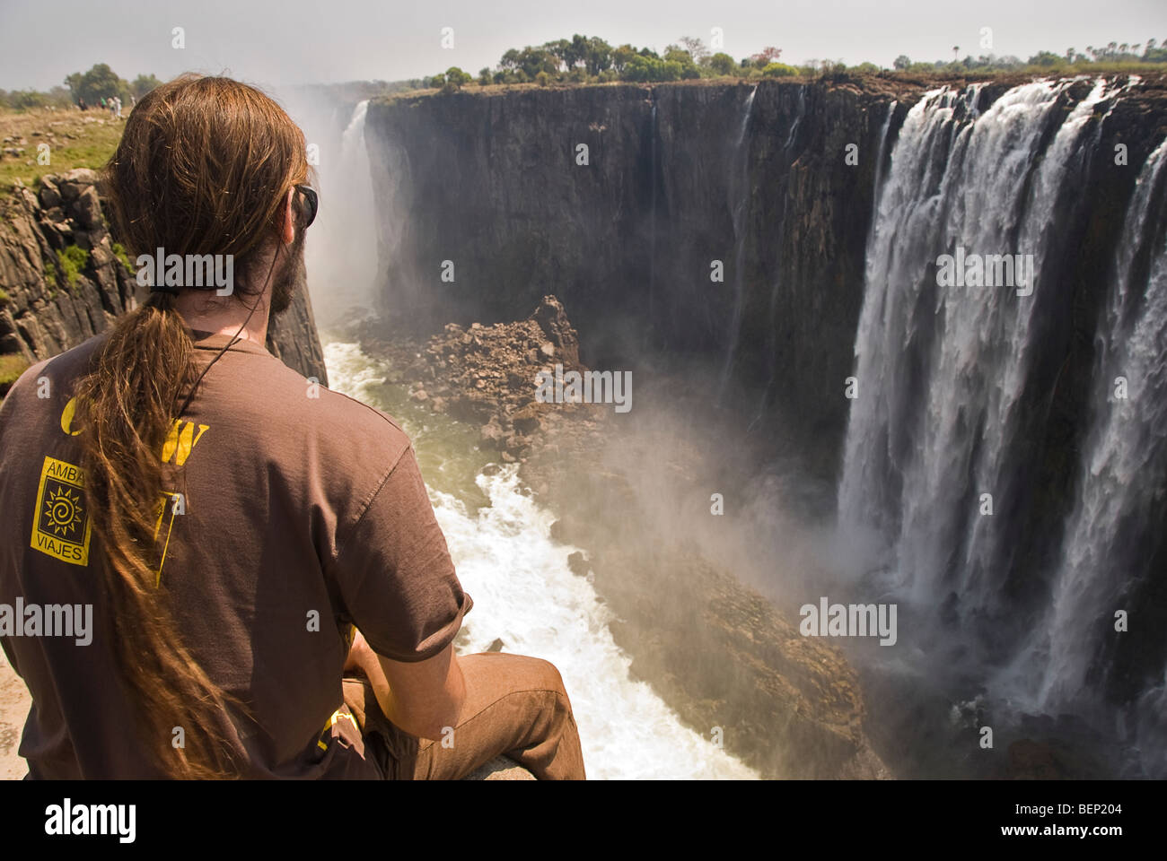 Man watching The Victoria falls sitting on the edge, Zimbabwe, Africa ...