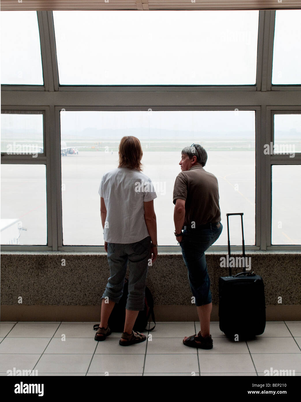 two travellers at an airport terminal waiting Stock Photo - Alamy