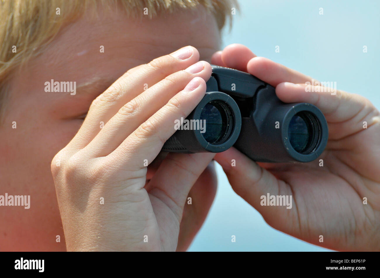Boy looking through binoculars to see things far away Stock Photo - Alamy
