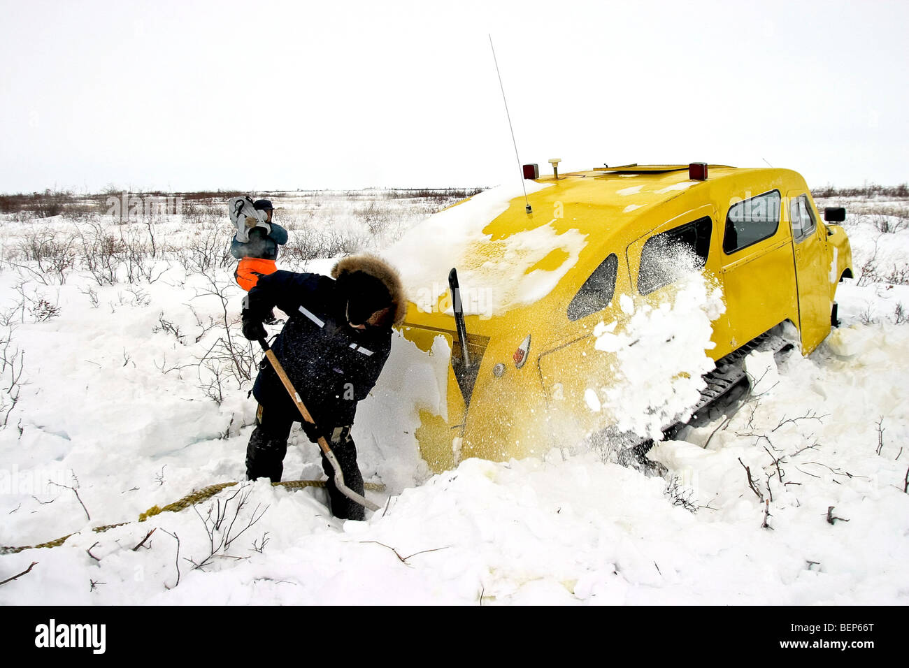 Men dig out stuck snowcoach from deep snow in wilderness tundra of ...