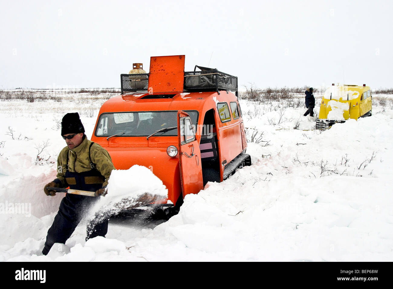 Men dig out stuck snowcoach from deep snow in wilderness tundra of ...