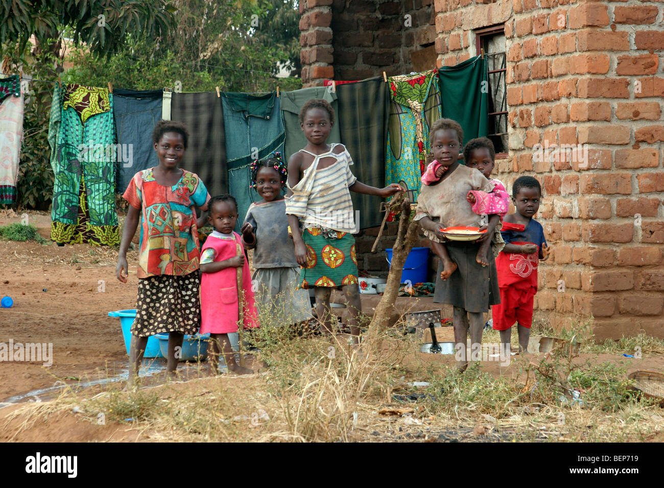 Black children posing in front of wash drying on clothesline in village ...