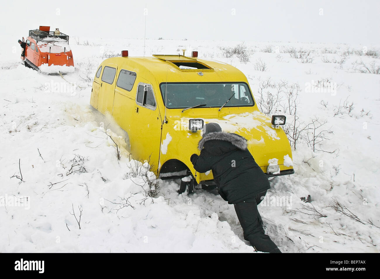 Men dig out stuck snowcoach from deep snow in wilderness tundra of ...