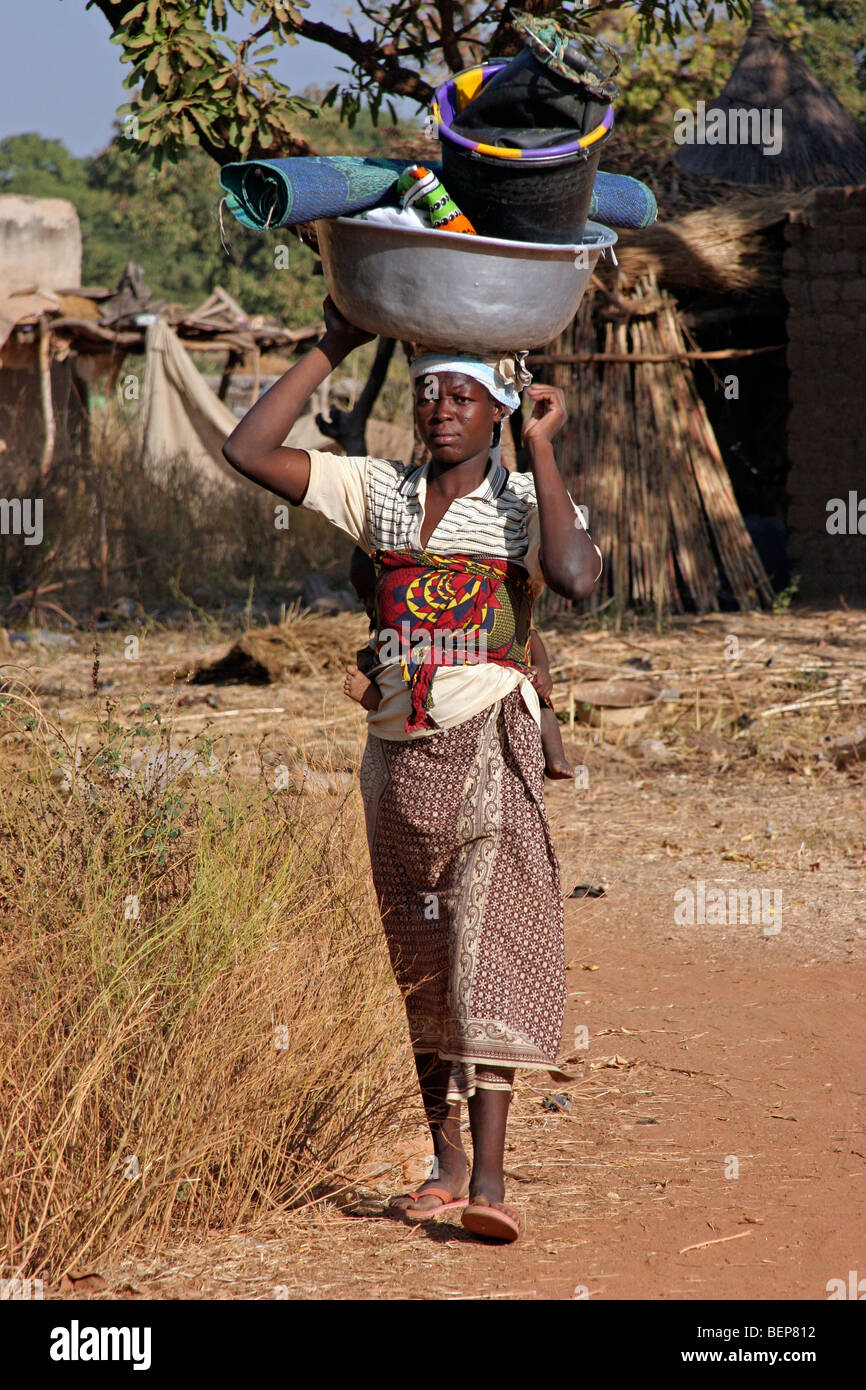 Black woman with baby on her back carrying merchandise on her head ...