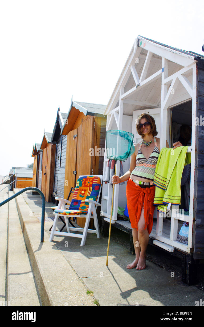 woman standing outside an English beach hut on an English summer's day ...