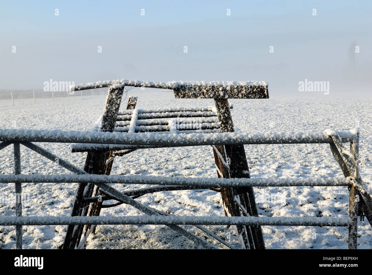 Snow and ice covered gate and fence in winter with bright blue sky ...