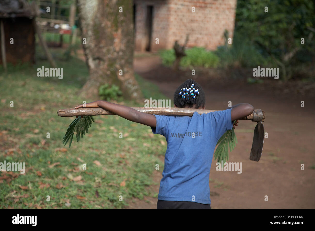 UGANDA The home of Ntanda Miria, Kayunga District. Girl carrying hoe ...