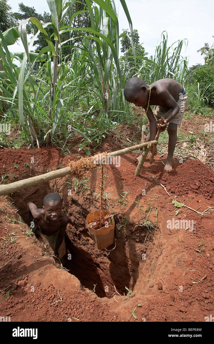UGANDA Boys digging a pit latrine, and hauling up the dirt with a winch ...