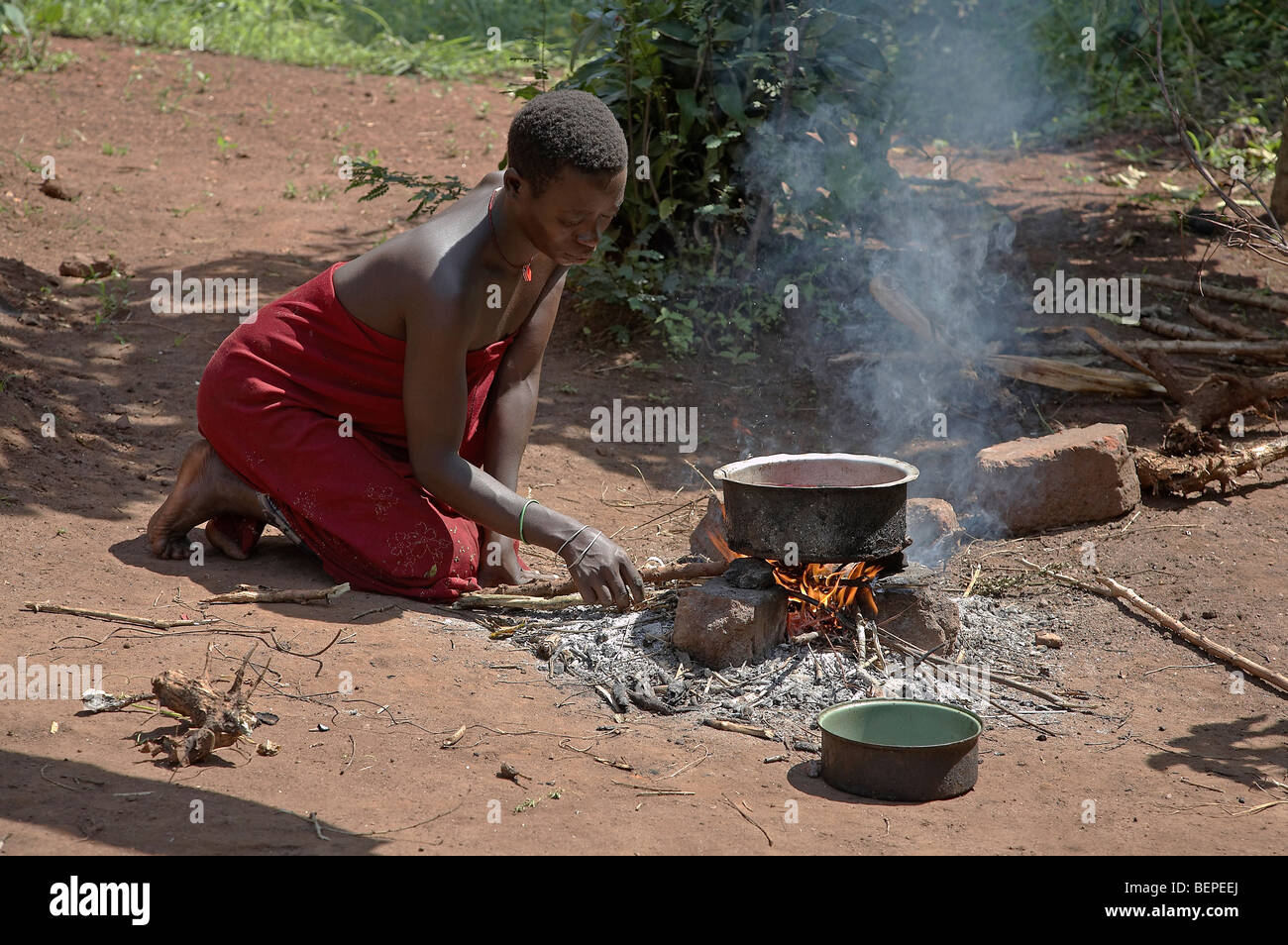 UGANDA A young woman, Proscovia, cooking on an open fire in front of ...