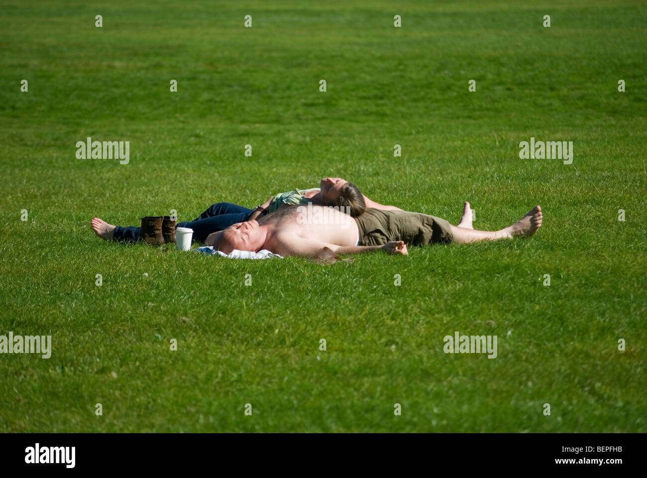 Bare chested man asleep in park with a woman resting on him at ...