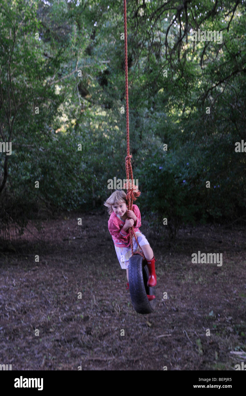 A six year old girl swinging on a tree rope Stock Photo - Alamy
