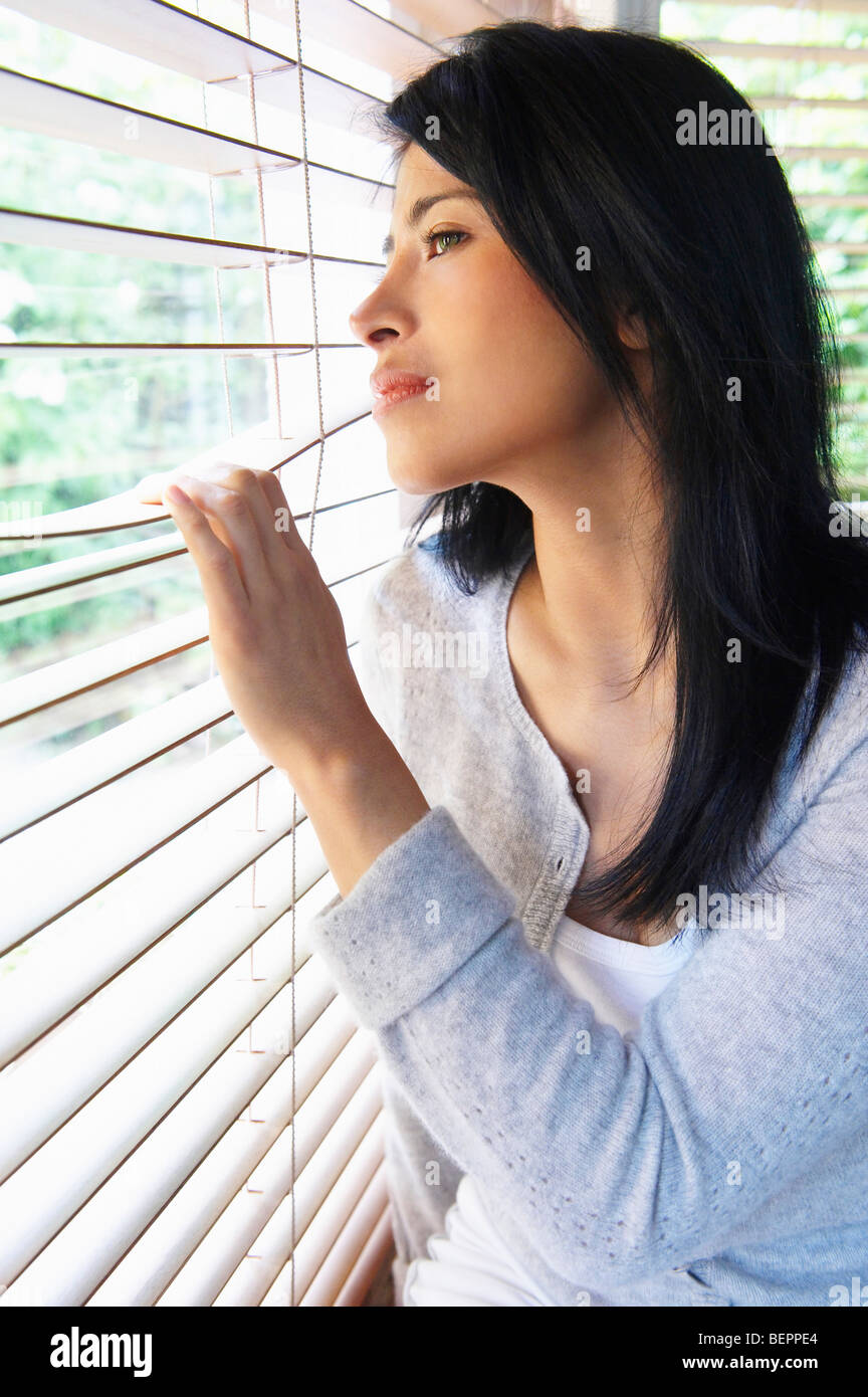 Woman looking through window Stock Photo - Alamy