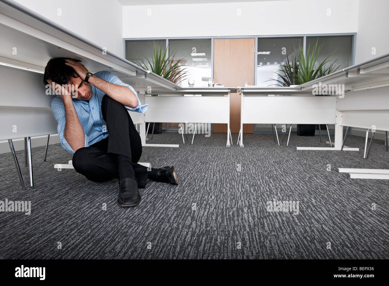man hiding under desk Stock Photo - Alamy