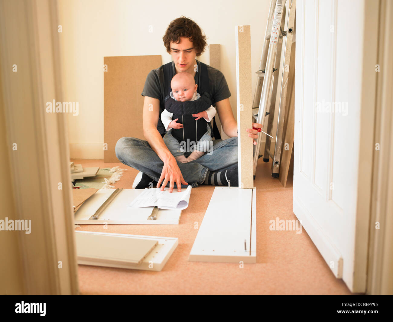 Man with baby building furniture Stock Photo - Alamy