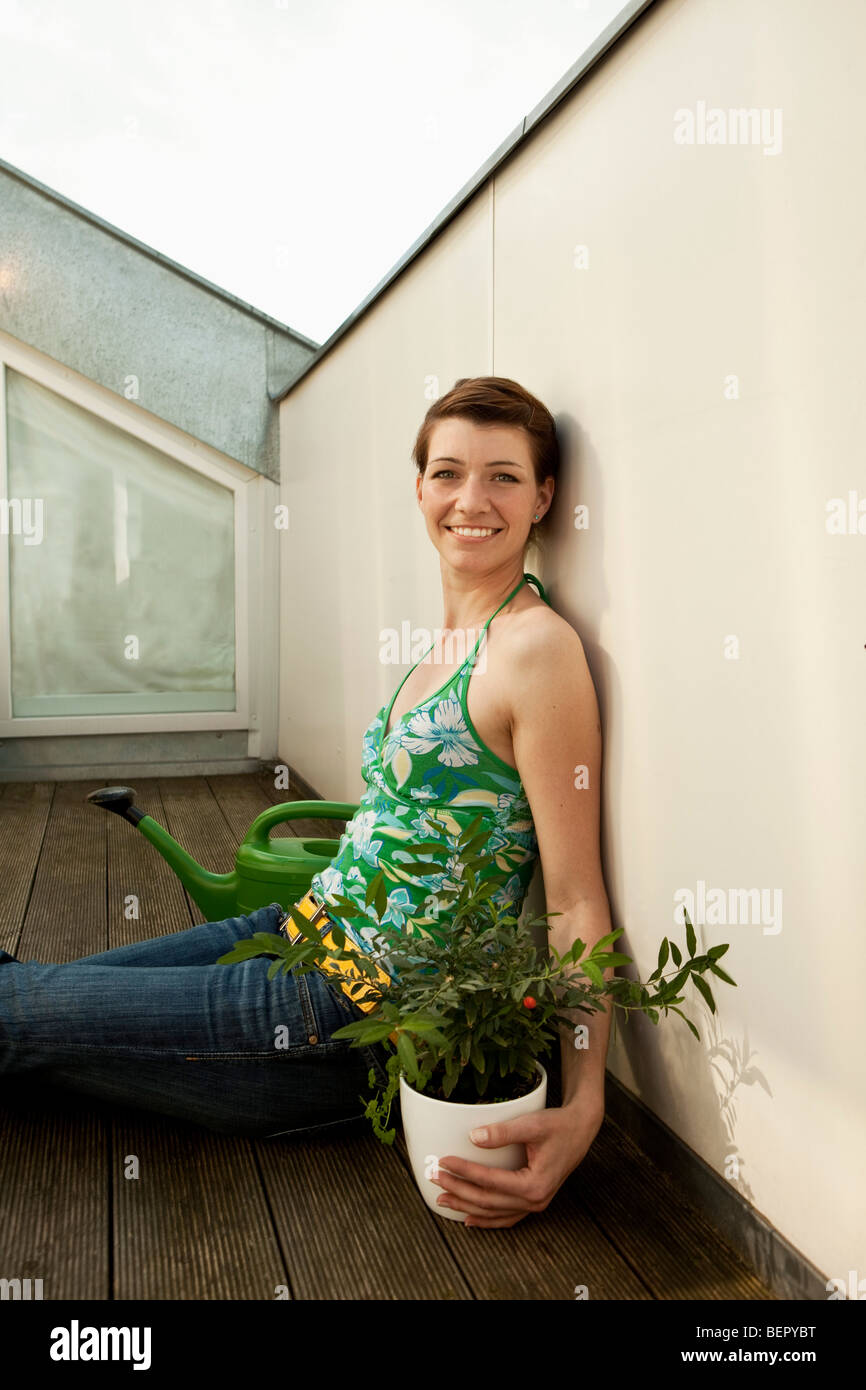 Young woman sitting on patio floor Stock Photo - Alamy