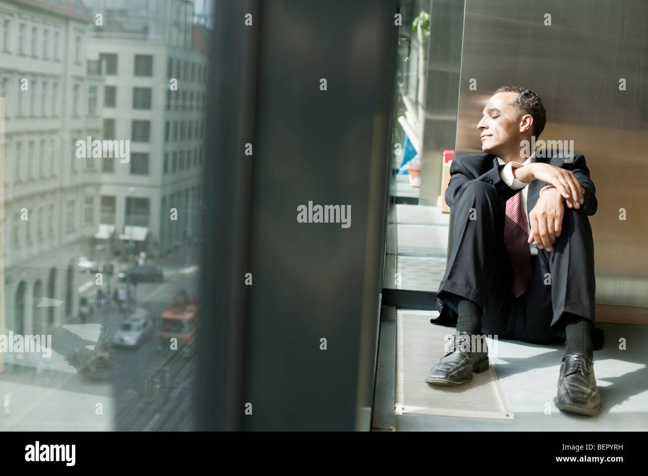 man on floor looking out a window Stock Photo - Alamy