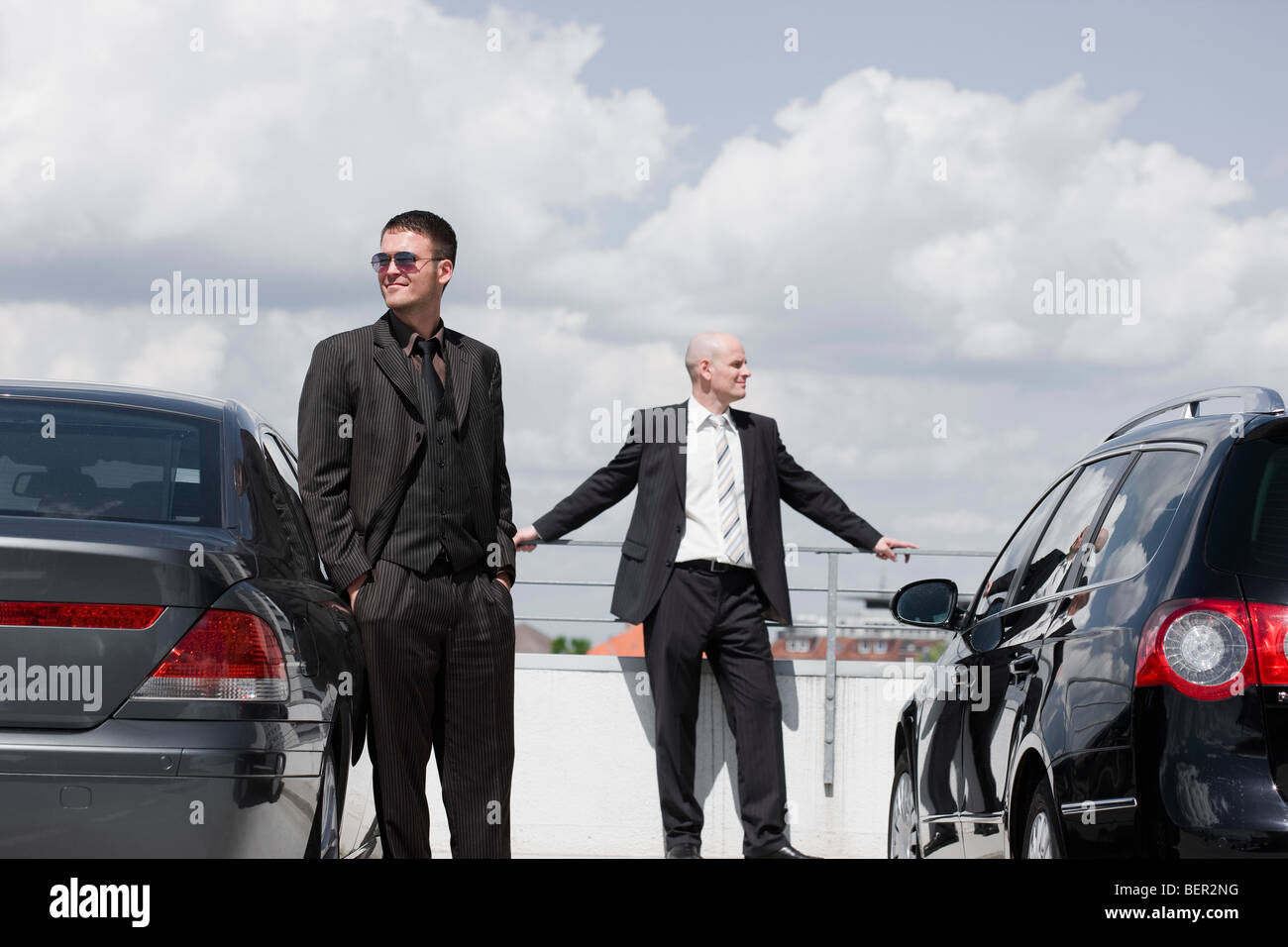 two business men standing between cars Stock Photo - Alamy
