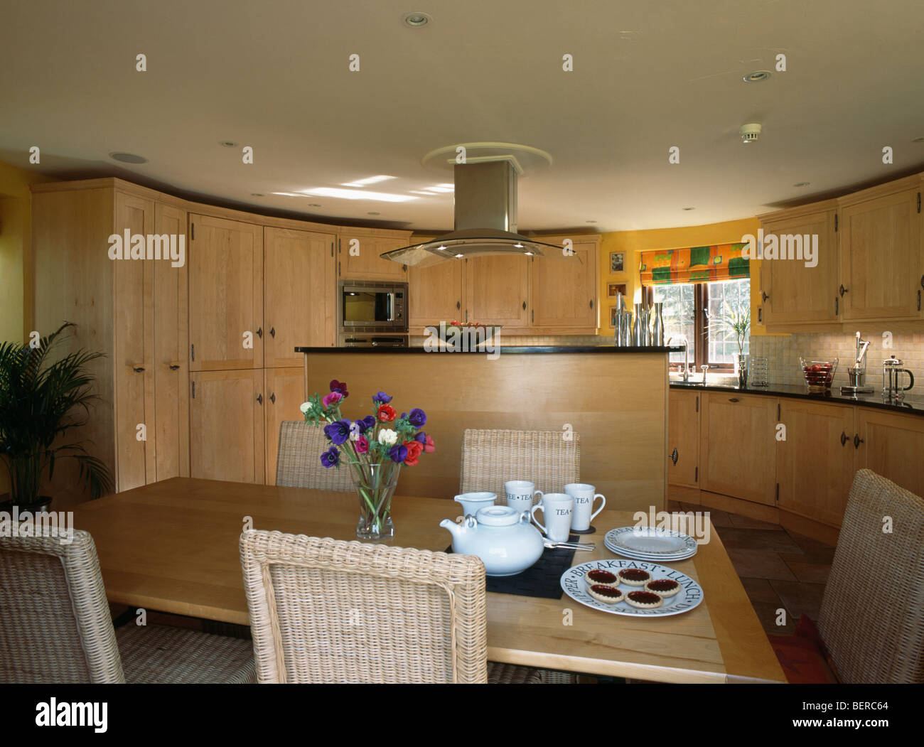 Wood table set for tea in modern country kitchen with pale wood fitted ...