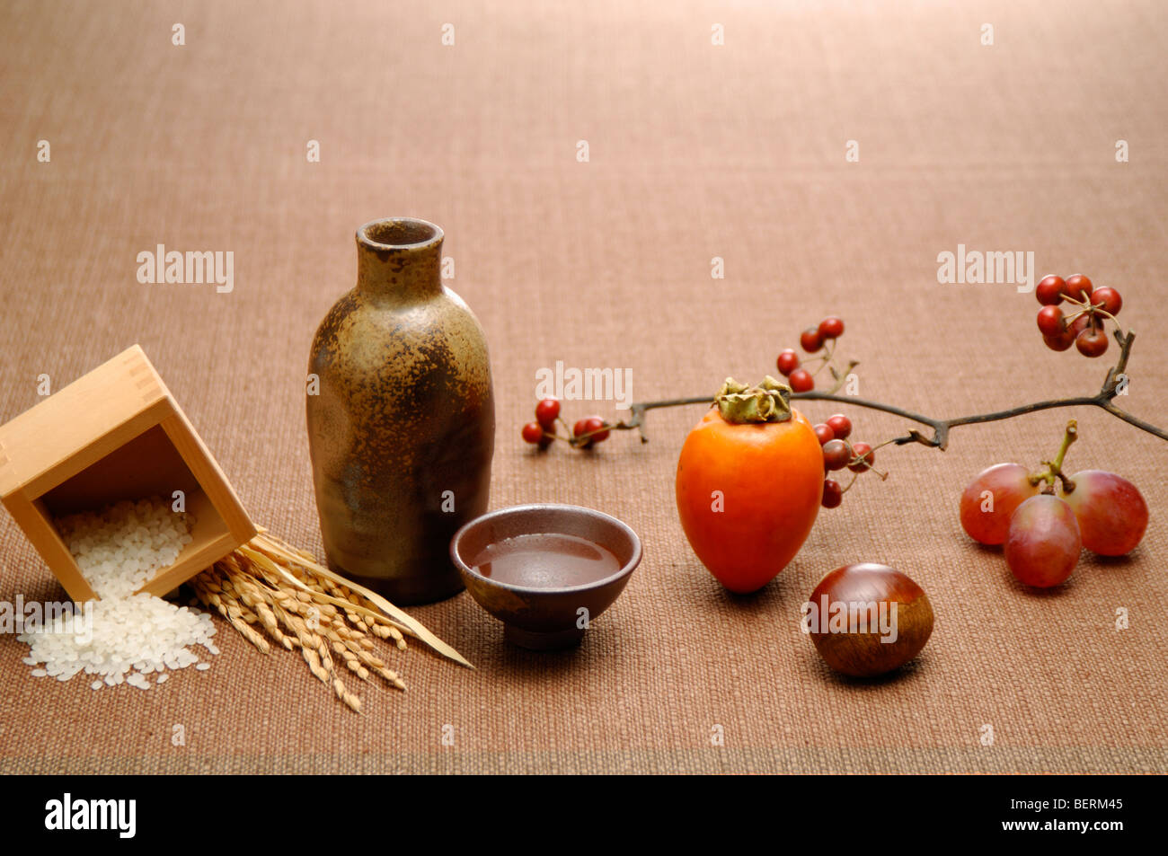 Sake, rice and fruits on brown background Stock Photo - Alamy