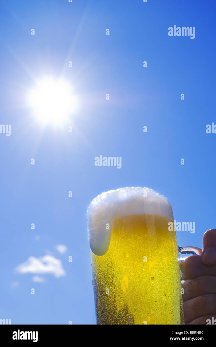 Man holding glass of beer under the sun Stock Photo - Alamy