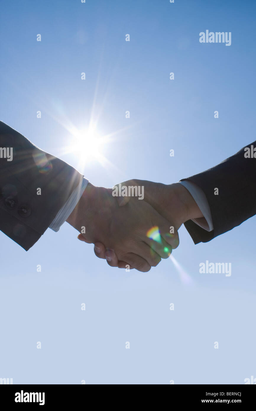 Two businessmen shaking hands under the sun Stock Photo - Alamy
