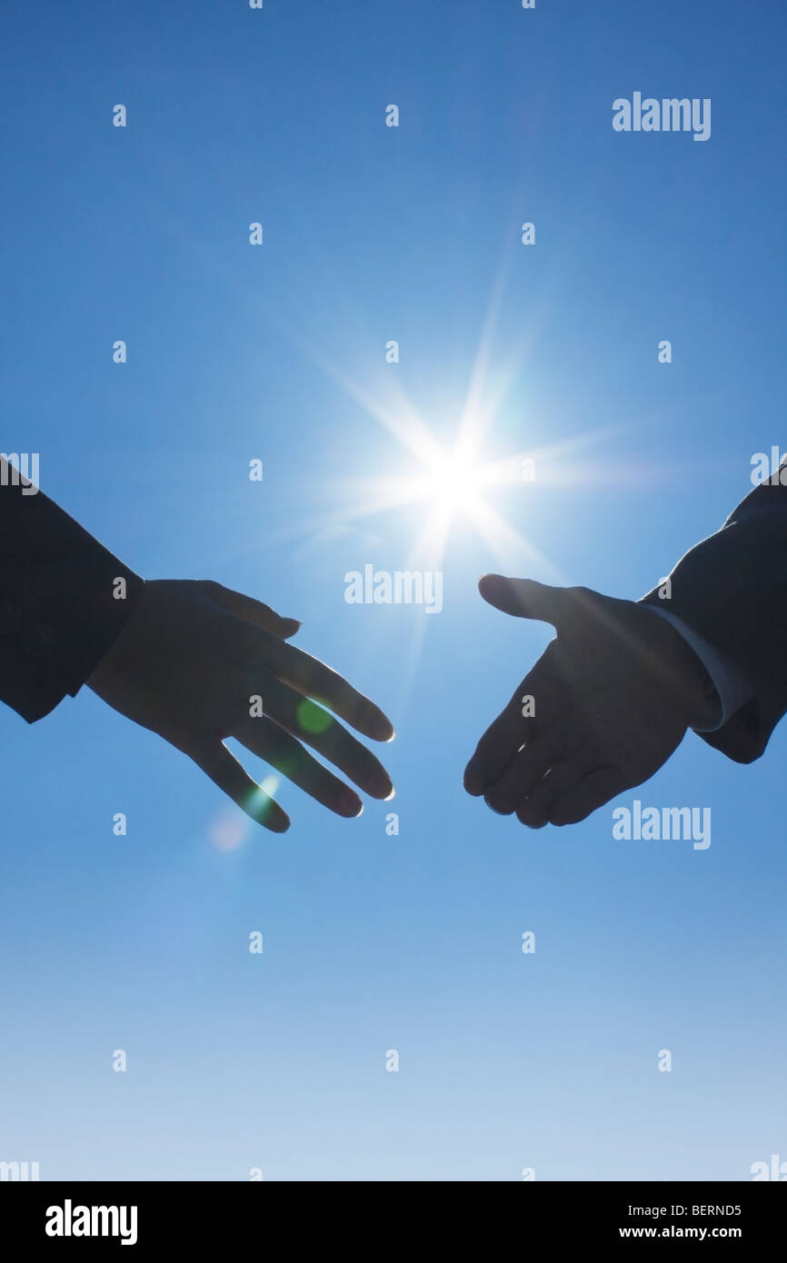 Two businessmen shaking hands under the sun Stock Photo - Alamy