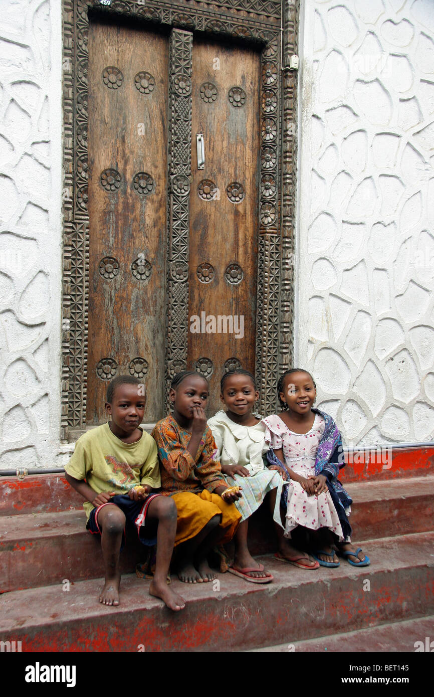 Four children sitting on stairs in the old medina of Stone Town ...