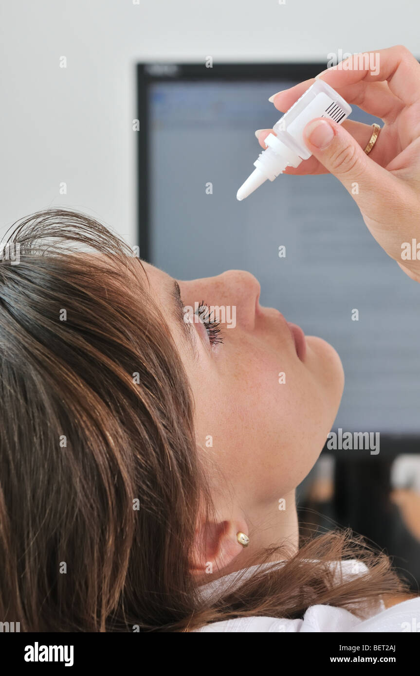 Detail of young business woman applying eye drops on workplace ...