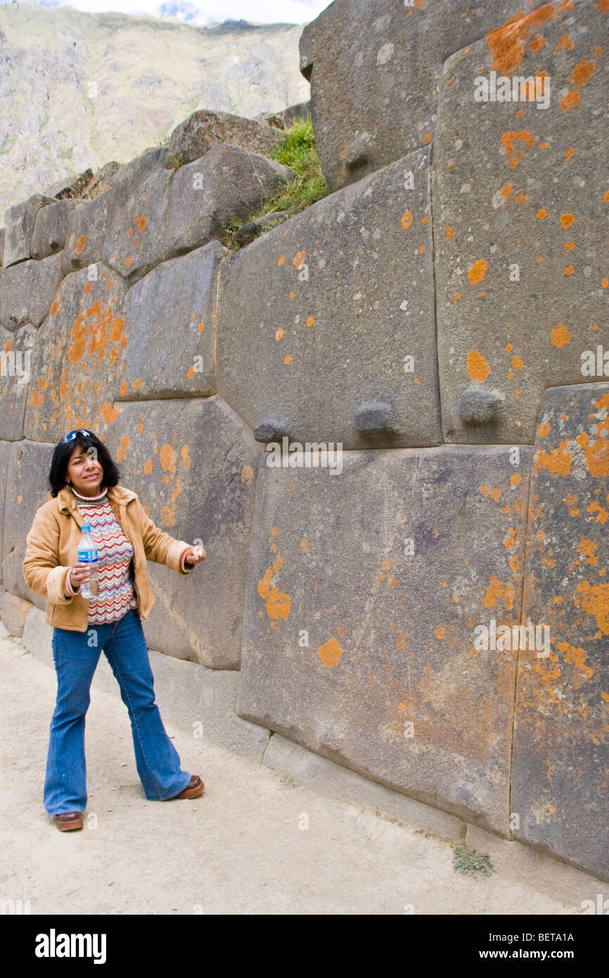 Peruvian woman stands next to the ancient Inca walls at Ollantaytambo ...
