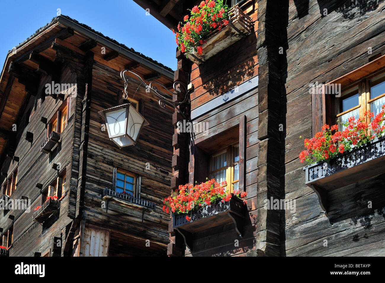 Traditional Swiss wooden houses / chalets decorated with geraniums in ...