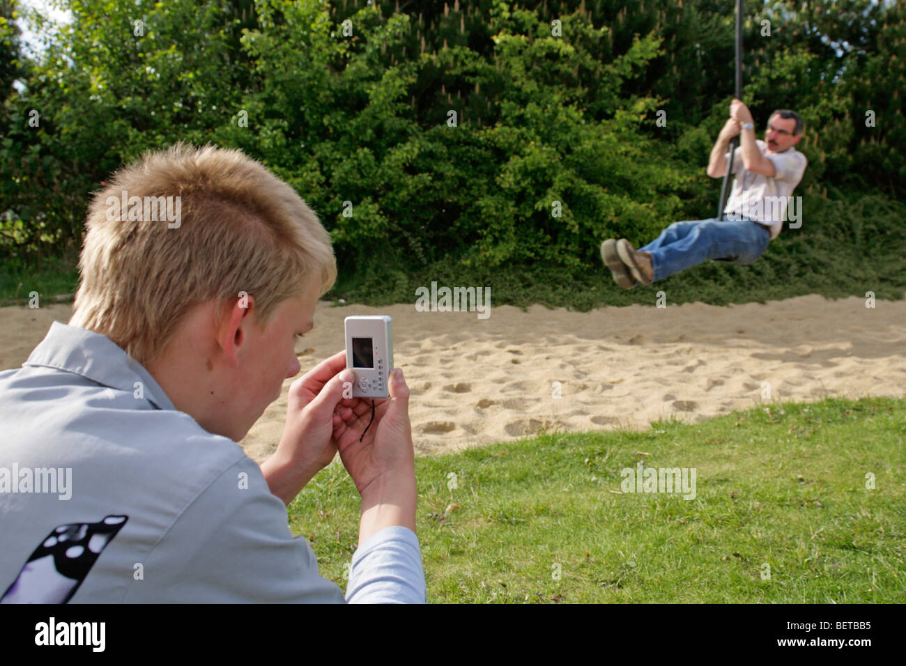 young boy taking a photo of his father on a rope slide Stock Photo - Alamy