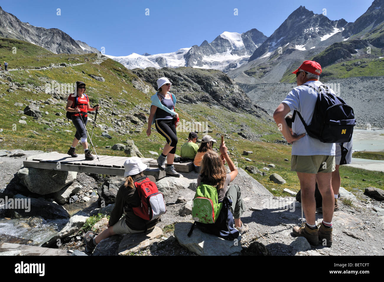 Tourists / Walkers walking along mountain path in the Swiss Pennine ...