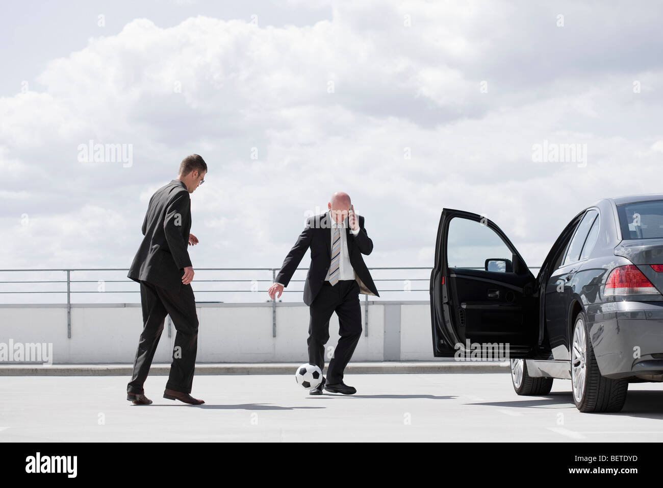 two men playing football near car Stock Photo - Alamy