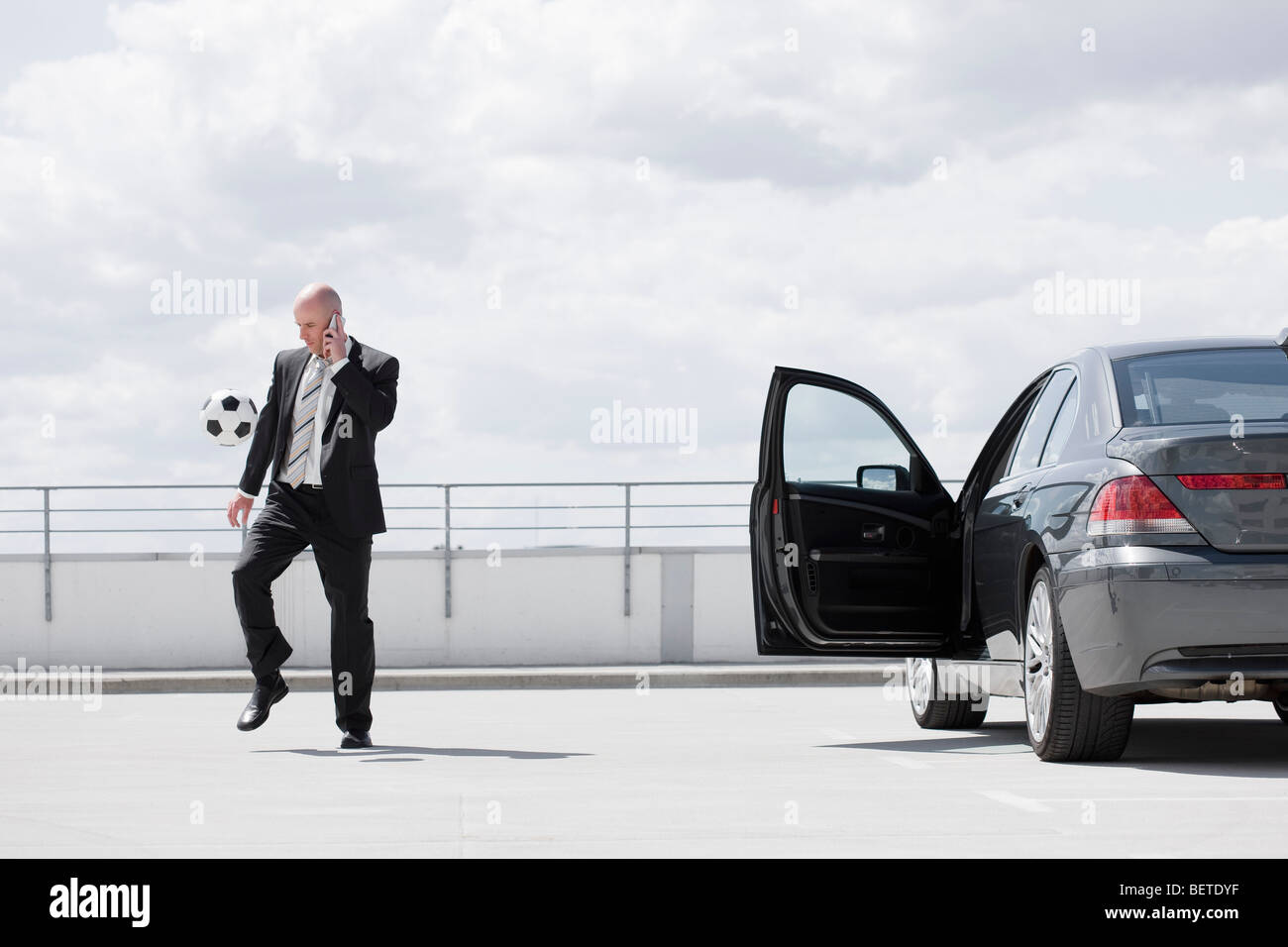 man playing football near car Stock Photo - Alamy