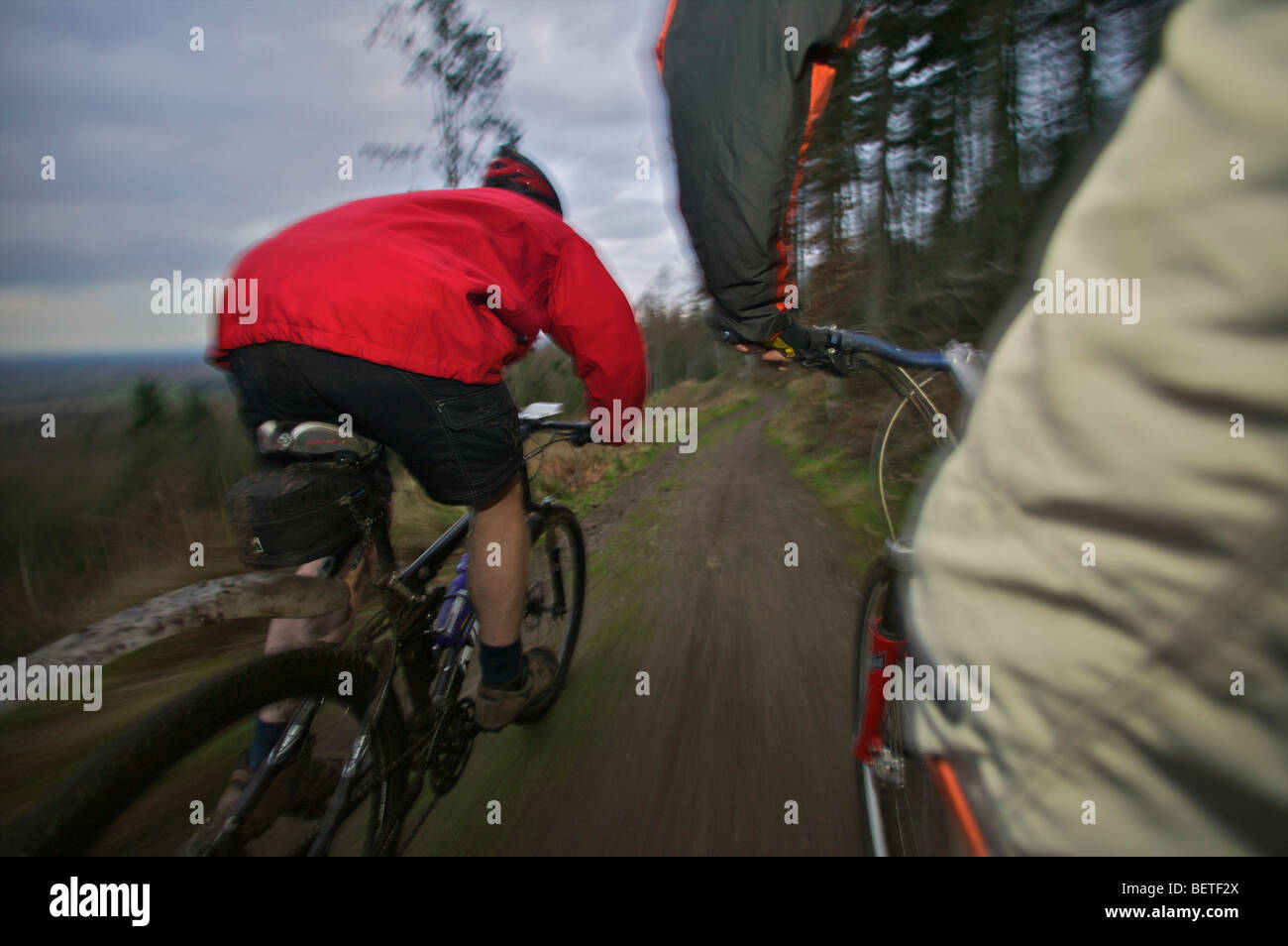 two mountain bikers riding down a track Stock Photo - Alamy