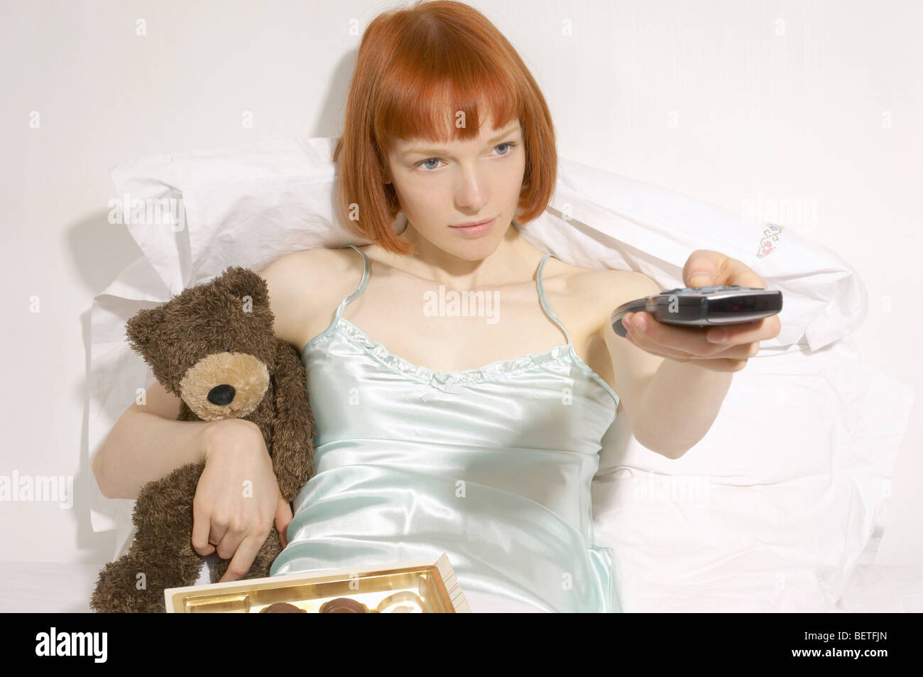 woman in bed with remote control Stock Photo - Alamy