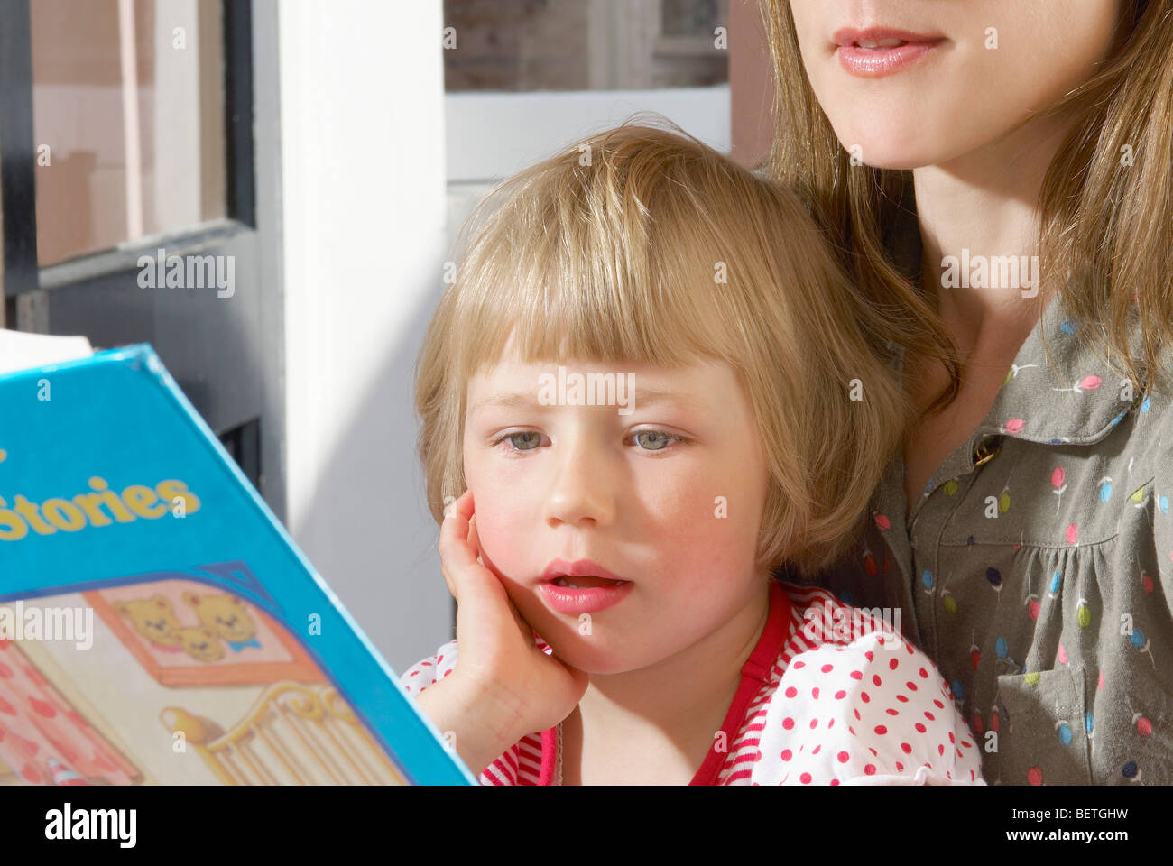 girl on mothers lap reading book Stock Photo - Alamy