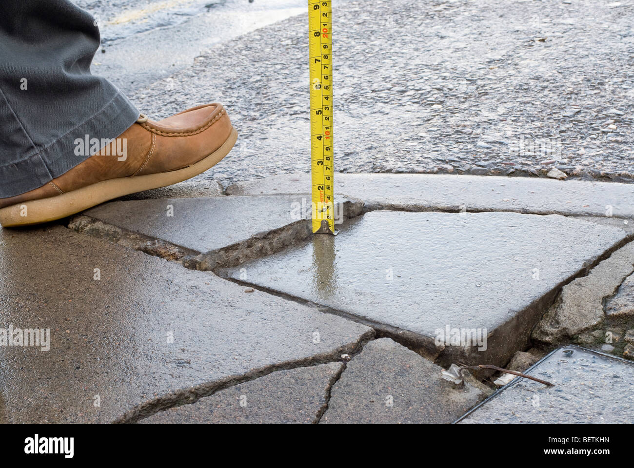 Measuring the height of broken paving stones Stock Photo - Alamy