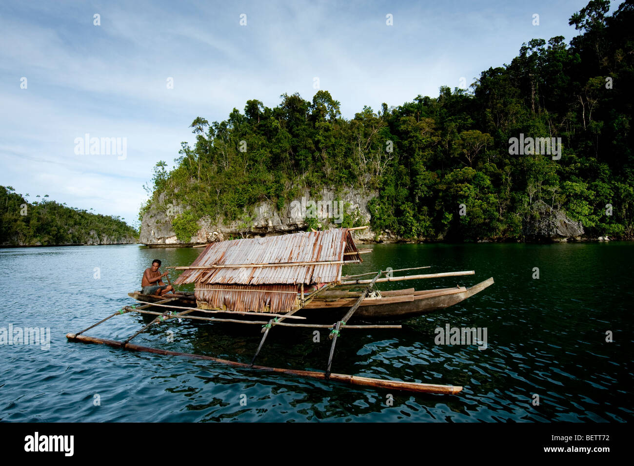 Native in outrigger canoe Stock Photo - Alamy