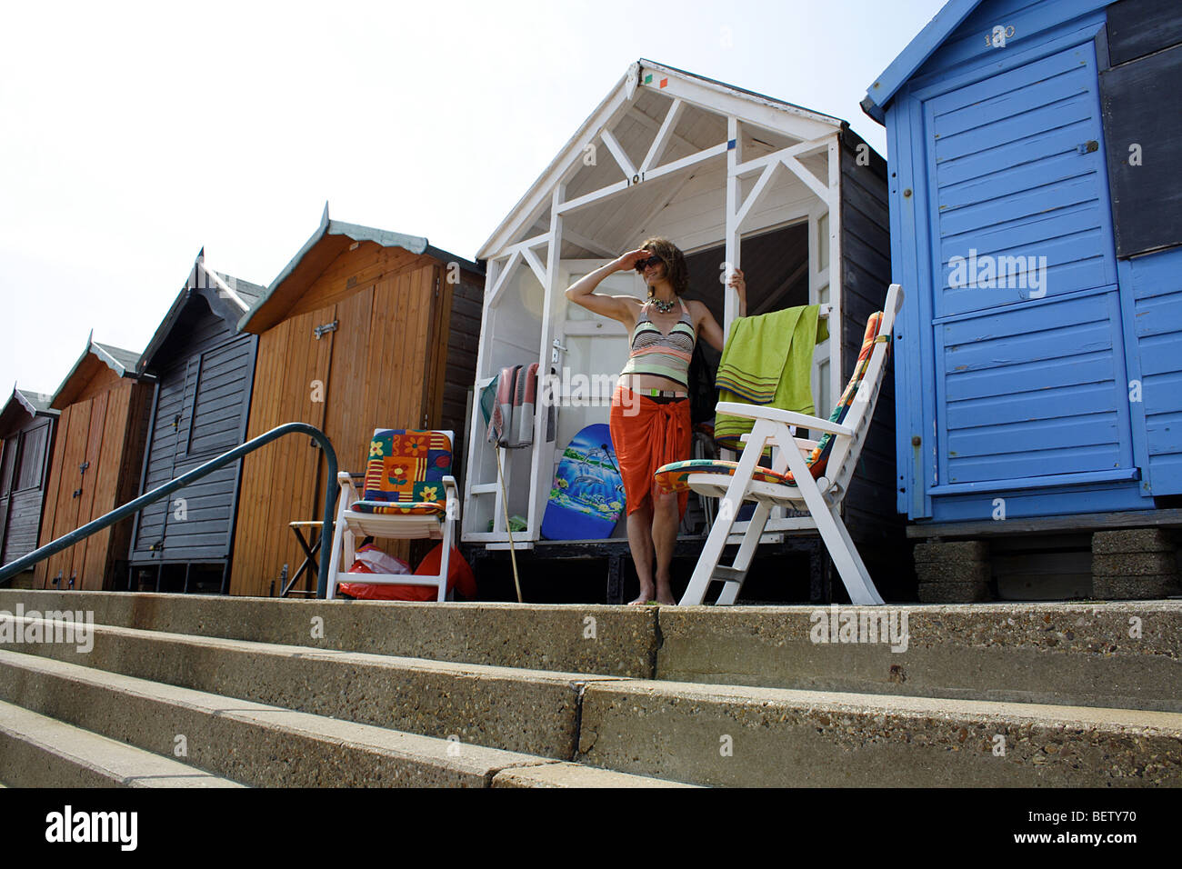 woman standing outside an English beach hut on a typical English summer ...